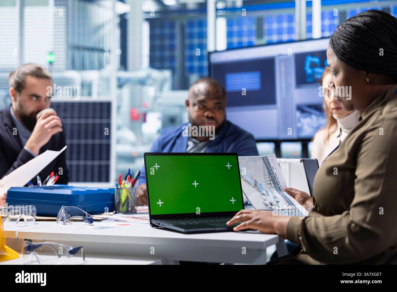 Factory management team look over schematics, planning work using ...
