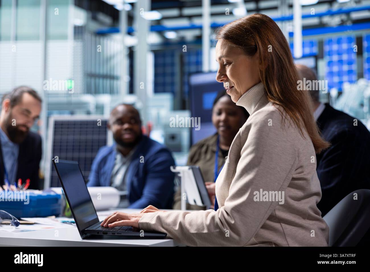 Photovoltaics factory management team analyzing data using laptop, reviewing system health ...