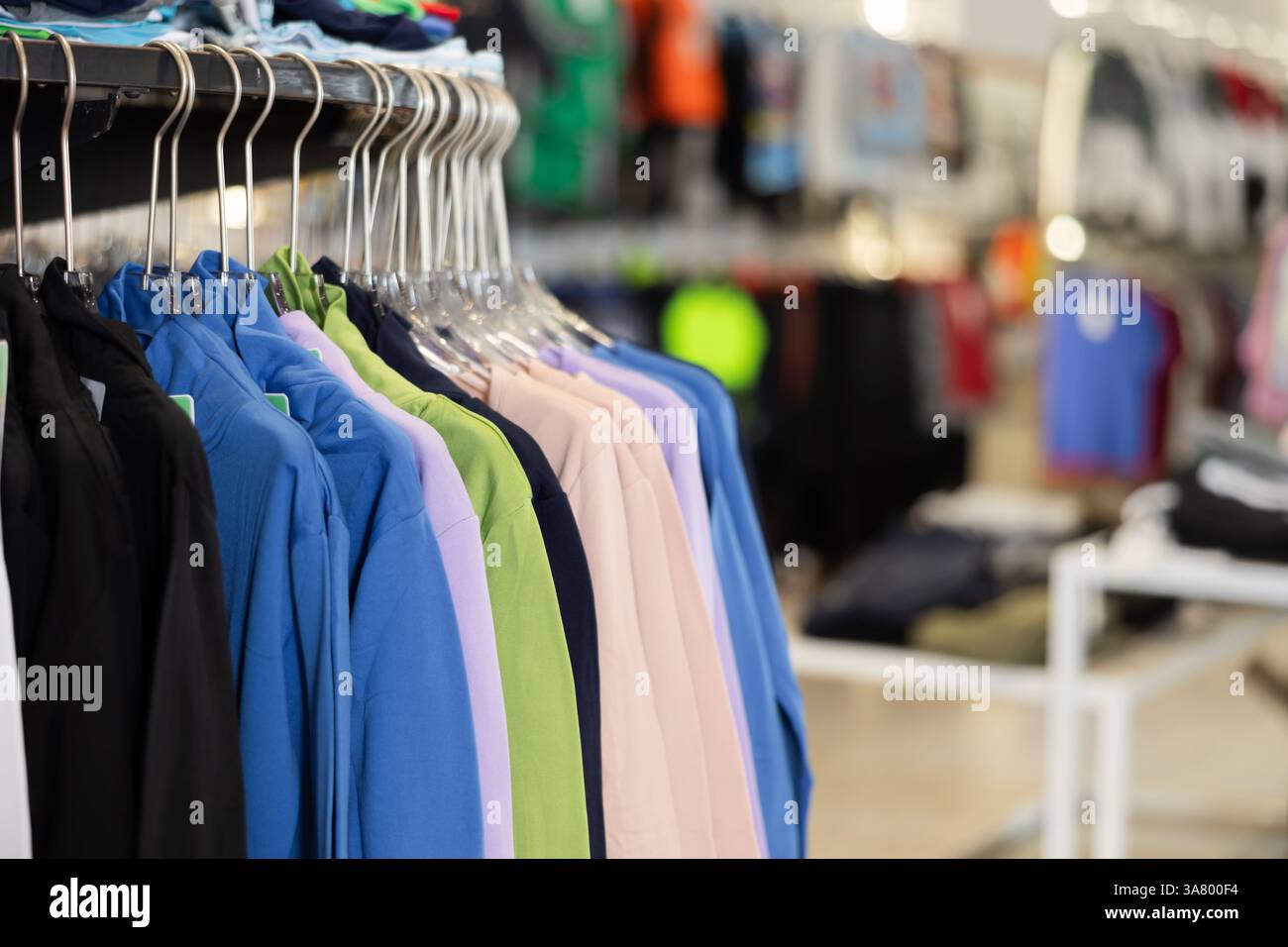 Colorful basic shirts hanging on stand in big clothing store Stock ...