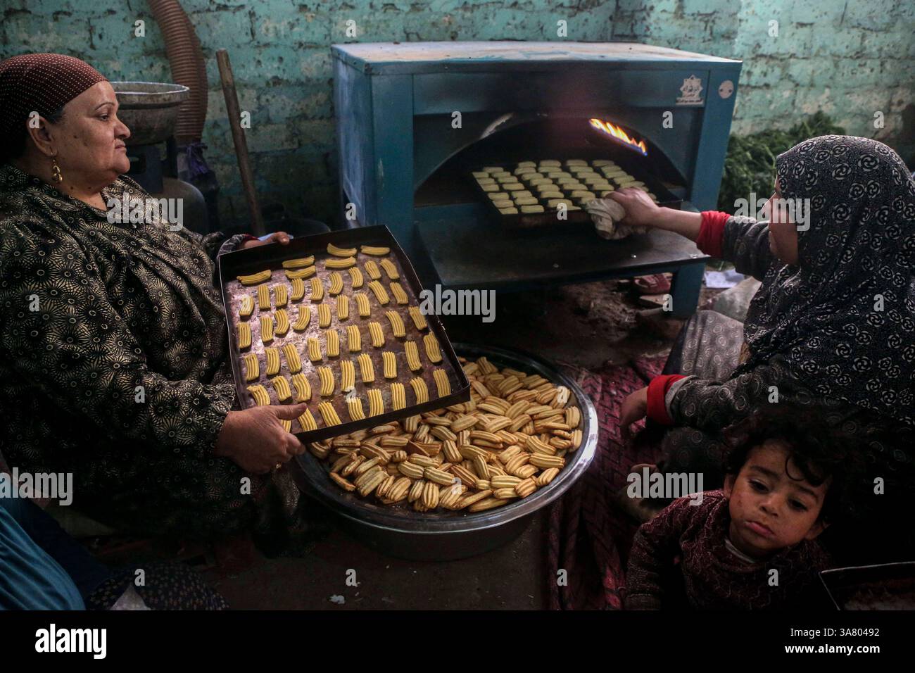 Cairo, Egypt. 27th Mar, 2025. Egyptian women make traditional cookies ...