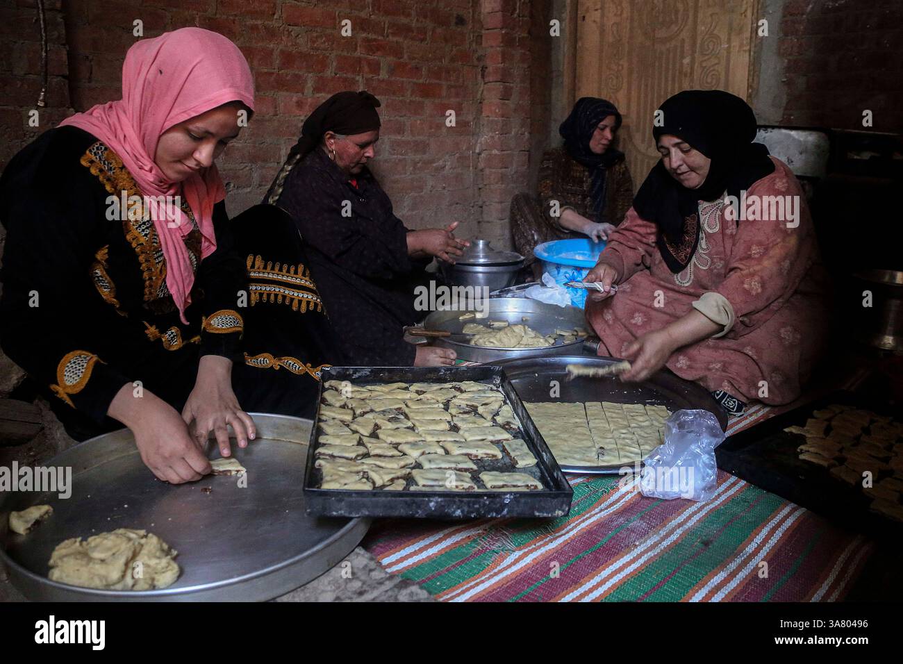 Cairo, Egypt. 27th Mar, 2025. Egyptian women make traditional cookies ...