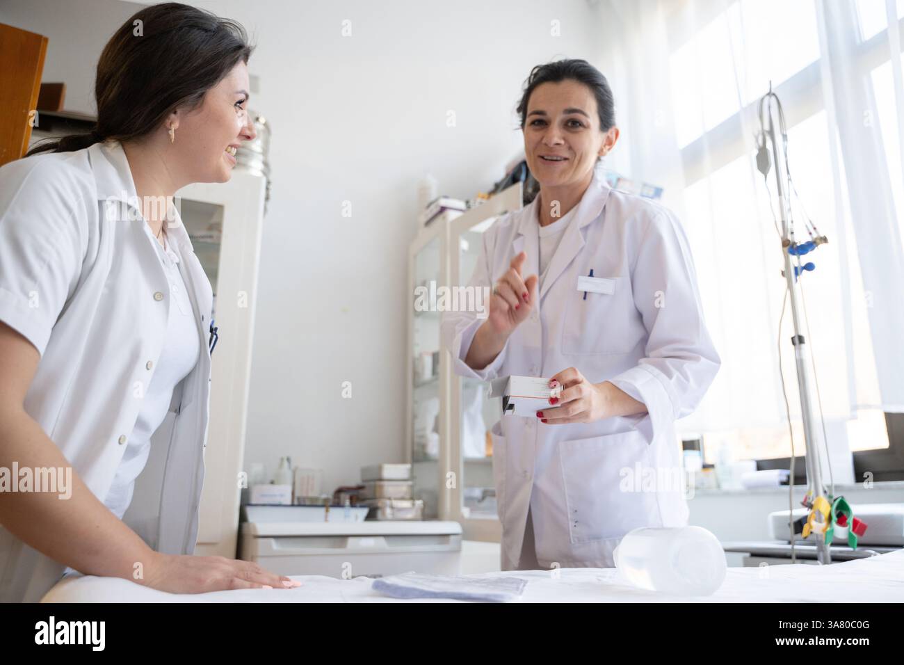Two nurses in a hospital laboratory are carefully inspecting and preparing medications for ...