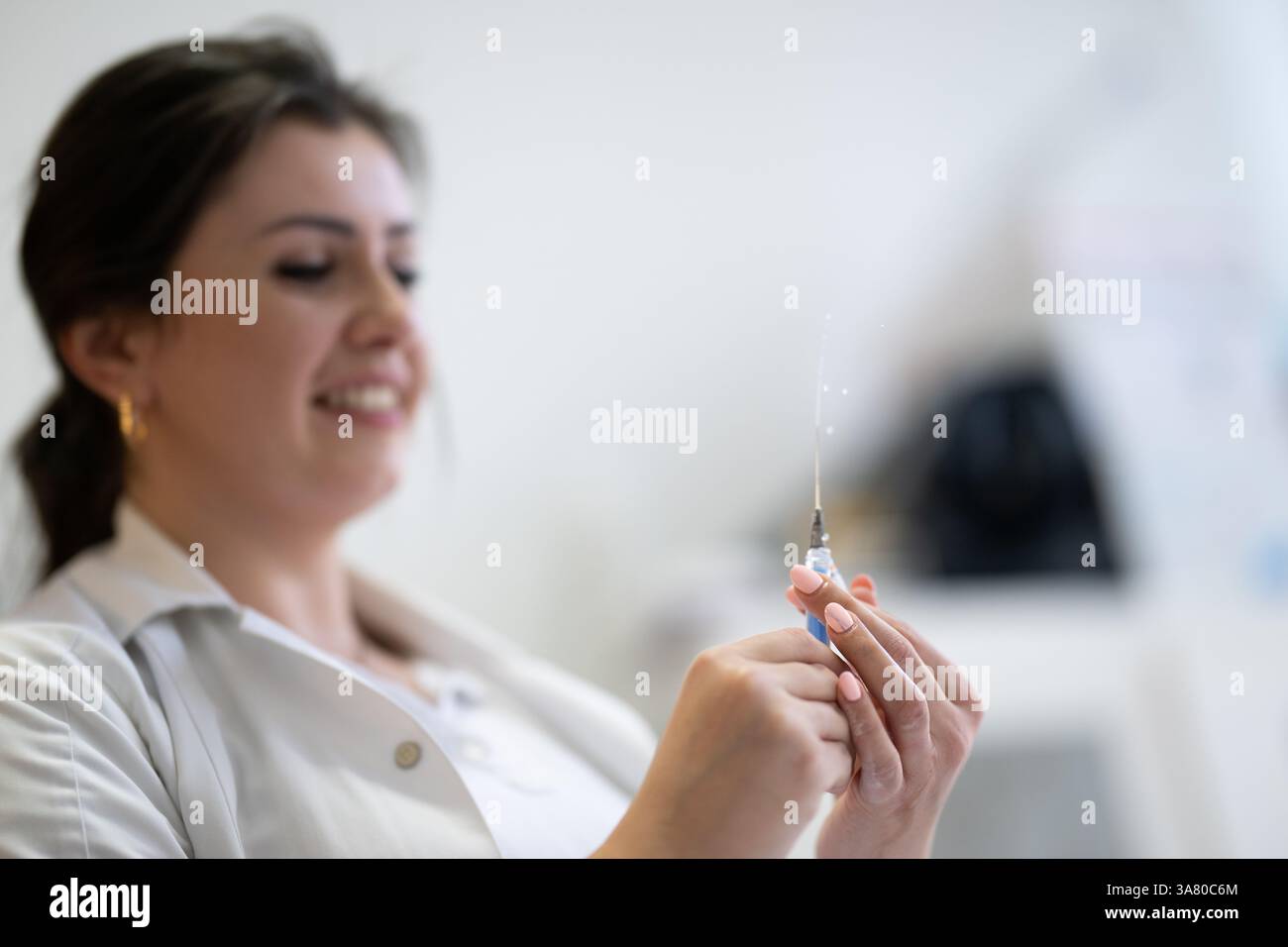A focused nurse in a white lab coat carefully prepares a syringe for an ...