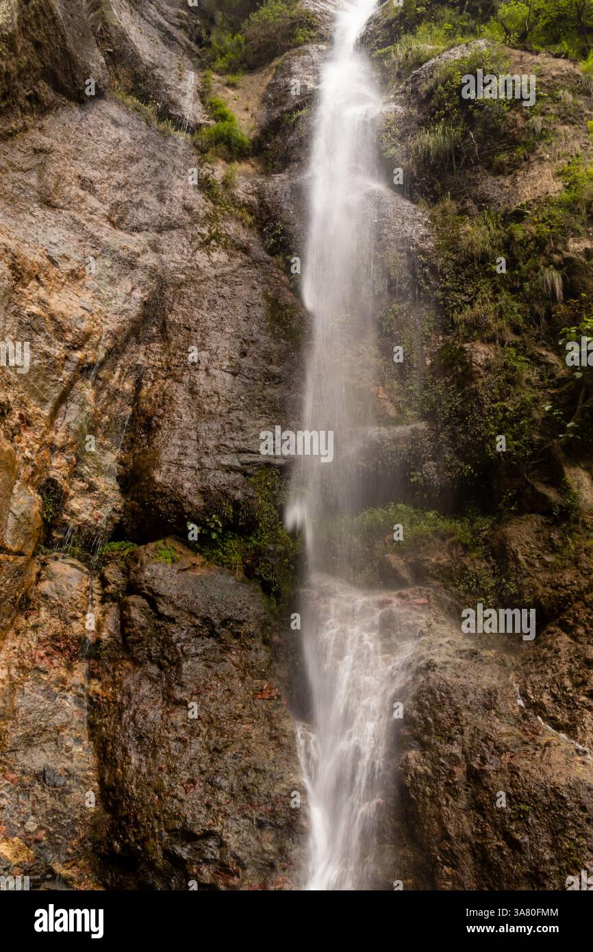 Tall waterfall cascading down a cliff amid natural rock formations ...