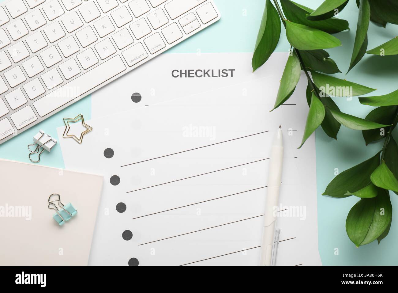 Checklist, keyboard, leaves and paper clips on light blue background ...