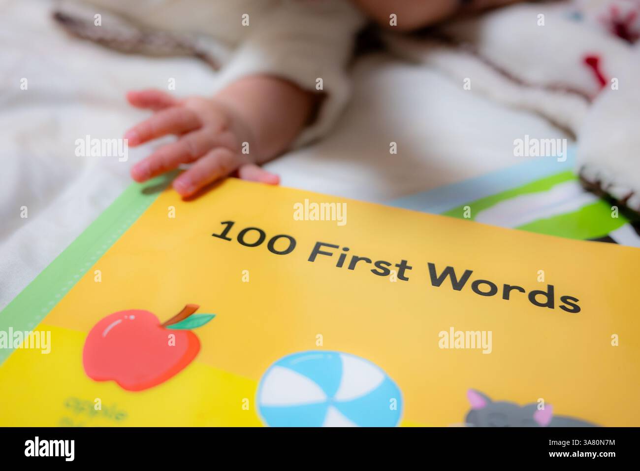 A baby reaches a book of 100 first words Stock Photo - Alamy