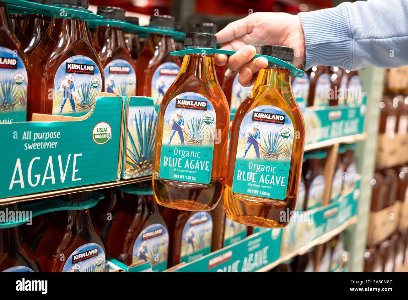 A shopper grabs Kirkland Organic Blue Agave in Costco Stock Photo - Alamy