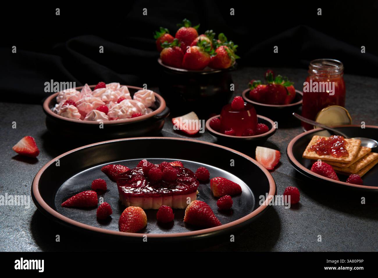Front view of strawberry dessert with raspberries on a black ceramic ...