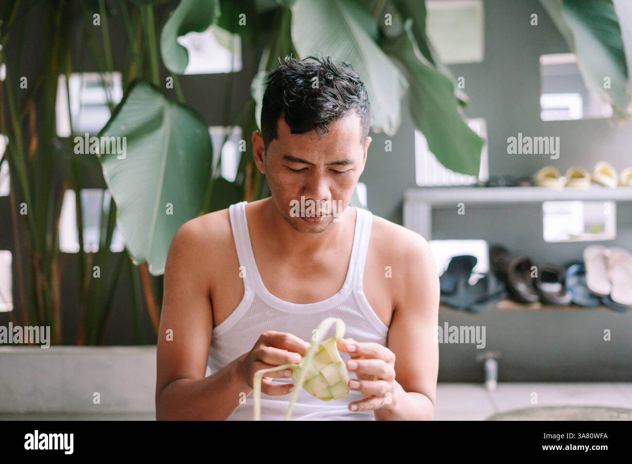 A man concentrates on weaving a ketupat, a traditional rice dumpling ...
