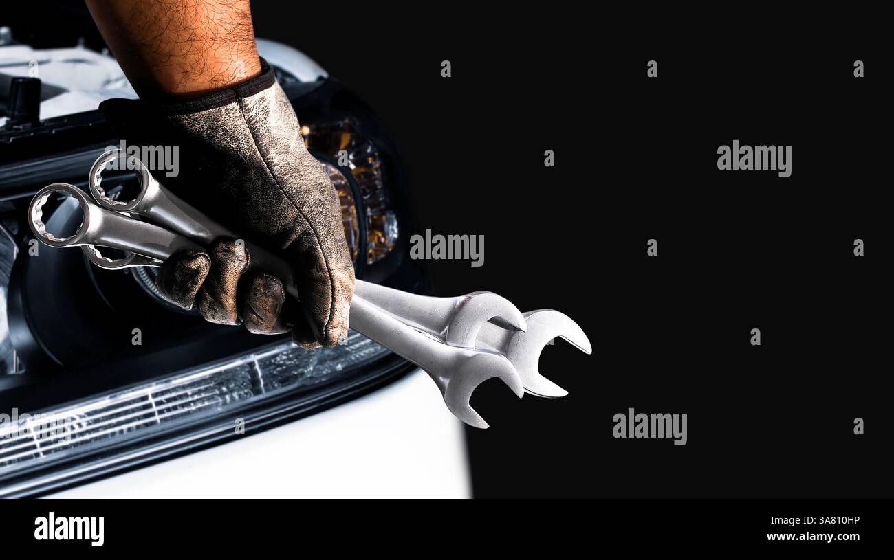 Mechanic holding wrenches in automotive workshop with copy space on ...