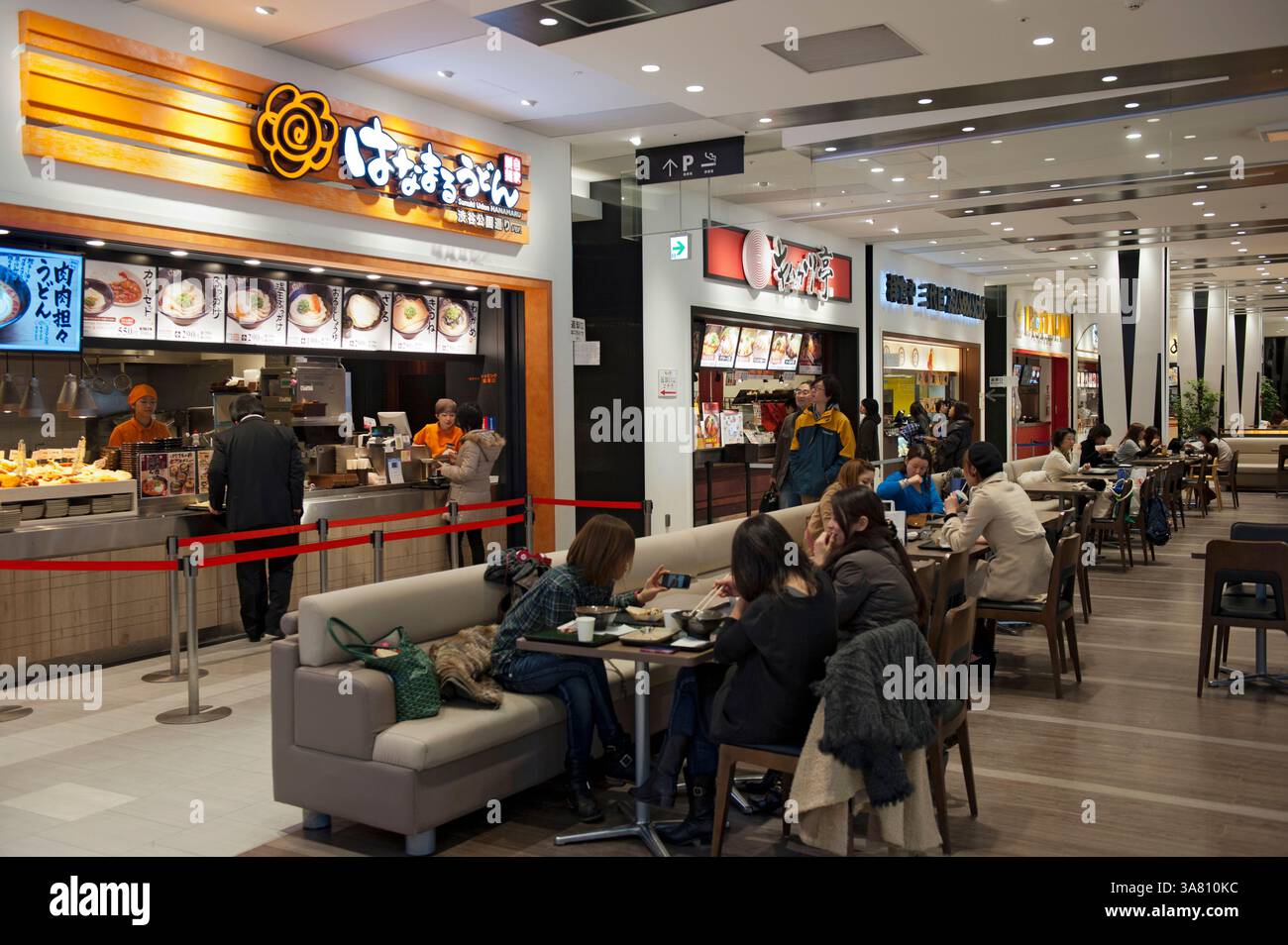 People taking a lunch break at a food court inside a shopping center ...