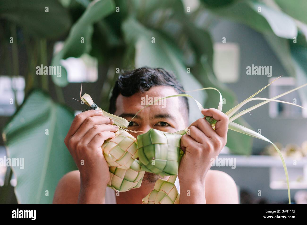 An Indonesian man holds Ketupat, a traditional rice dumpling made from ...