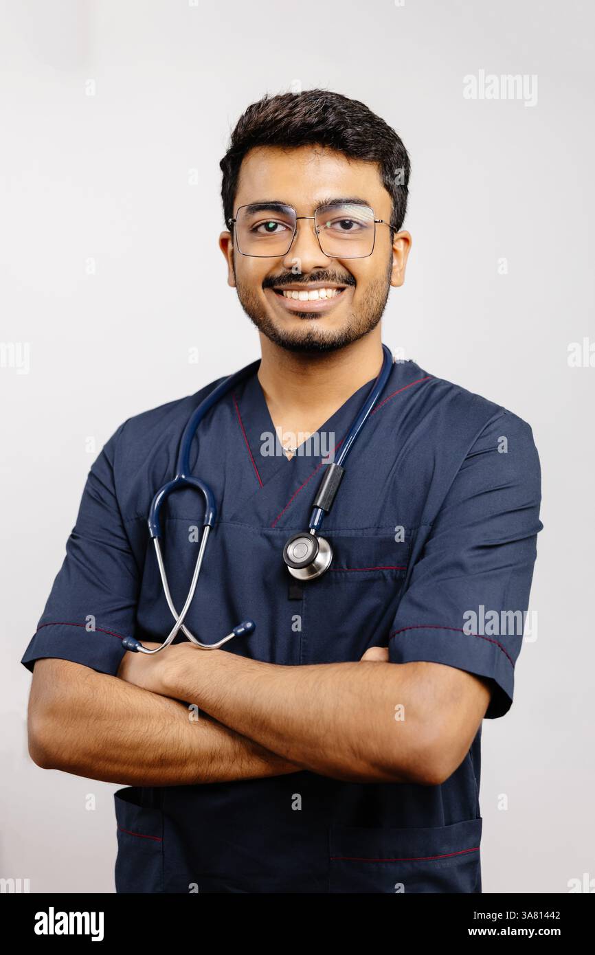 Confident Indian doctor smiling with arms crossed, wearing glasses and stethoscope, representing ...