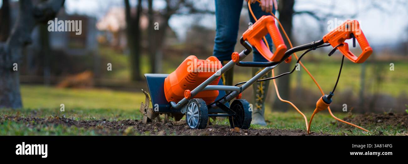 Gardener preparing garden beds for planting. Using rotovator, garden ...