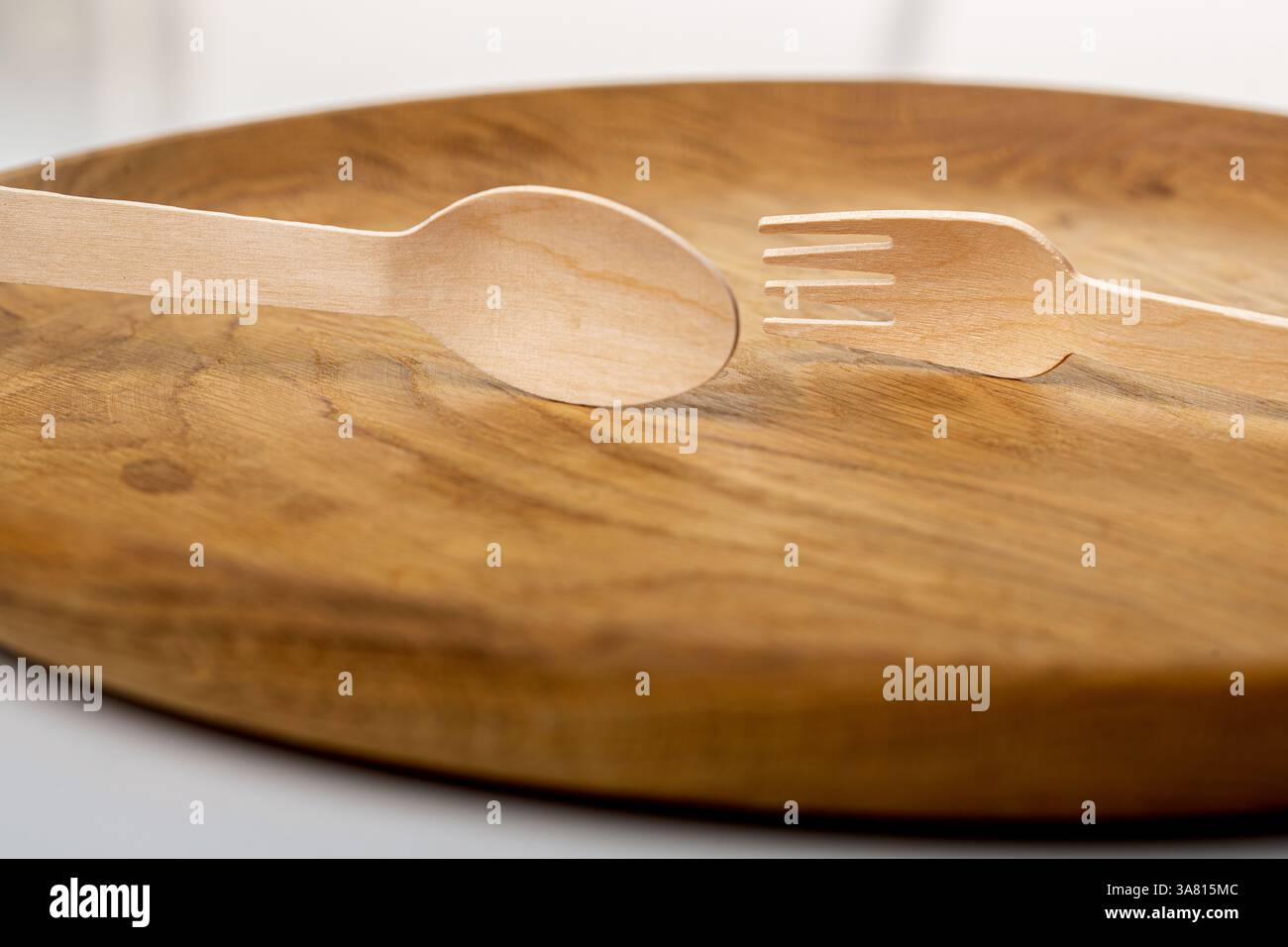 Wooden disposable spoon and fork lying on a round wooden oak dish. Eco ...