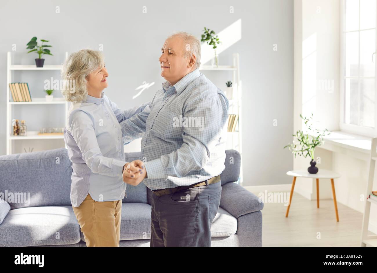 Happy active old retired senior couple dancing close in modern living ...