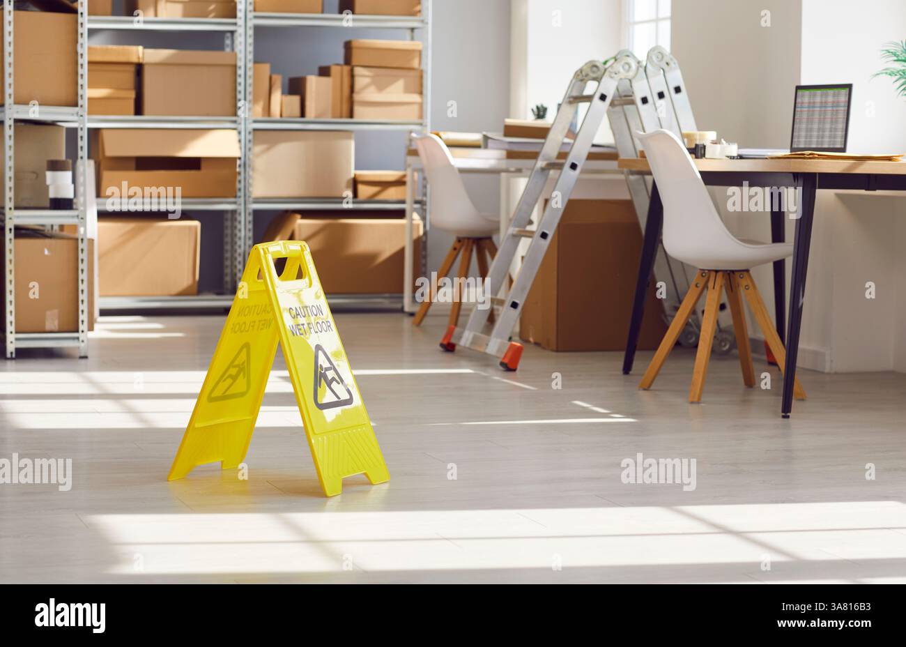 Caution wet floor sign in empty office in warehouse with shelves filled ...