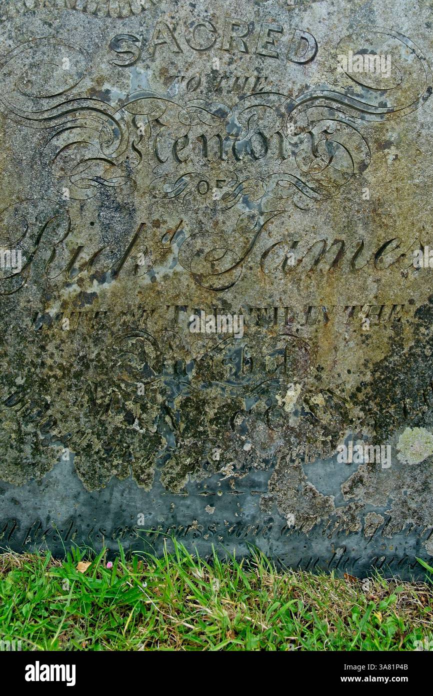 Old weathered gravestone with lichen growing on the surface giving the ...