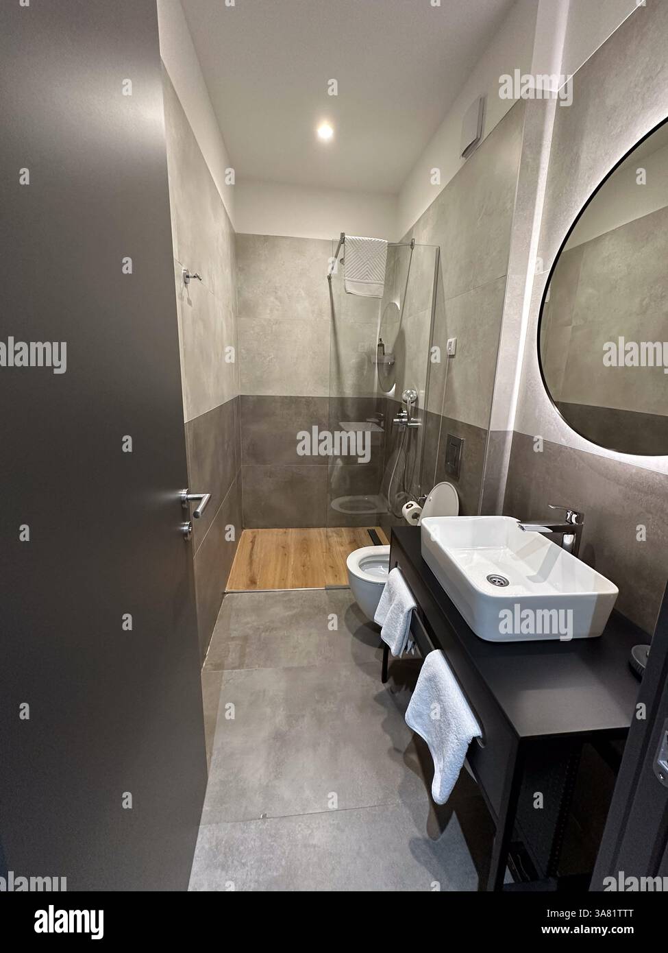 Contemporary hotel bathroom with walk-in shower and round mirror ...