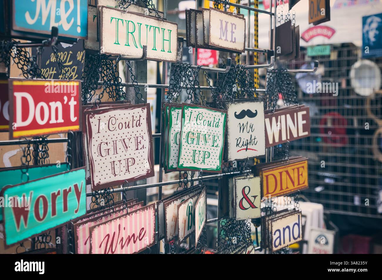 Decorative hanging signs with text on display at Brick Lane market in ...
