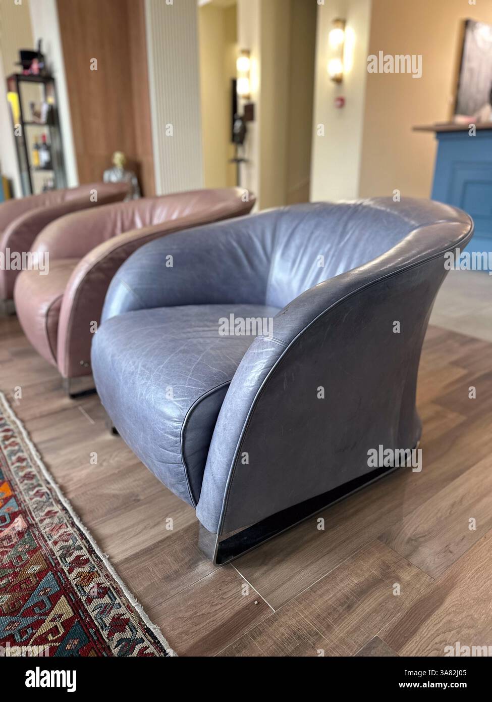 Comfortable leather armchairs in hotel lounge area with wooden floor and carpet. Modern interior ...