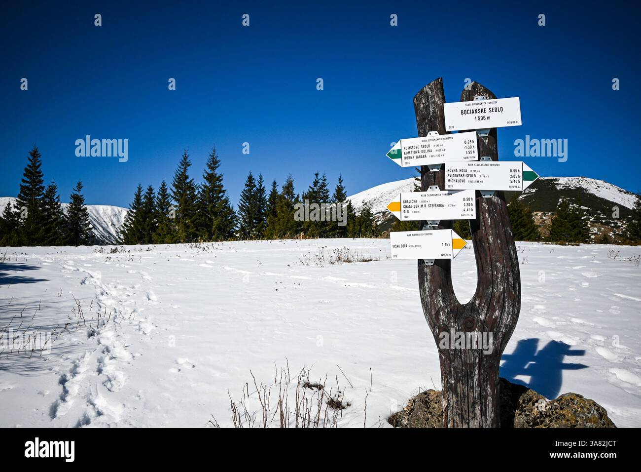 Wooden signpost showing different hiking trails and distances in snowy ...