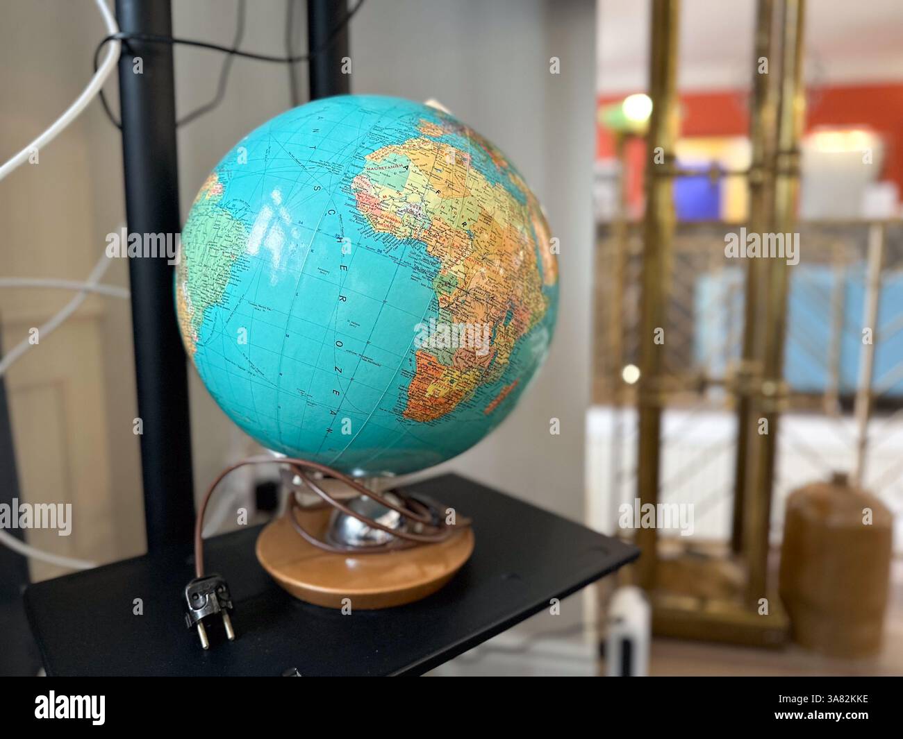 Rotating world globe with electric cord placed on dark shelf in retro ...