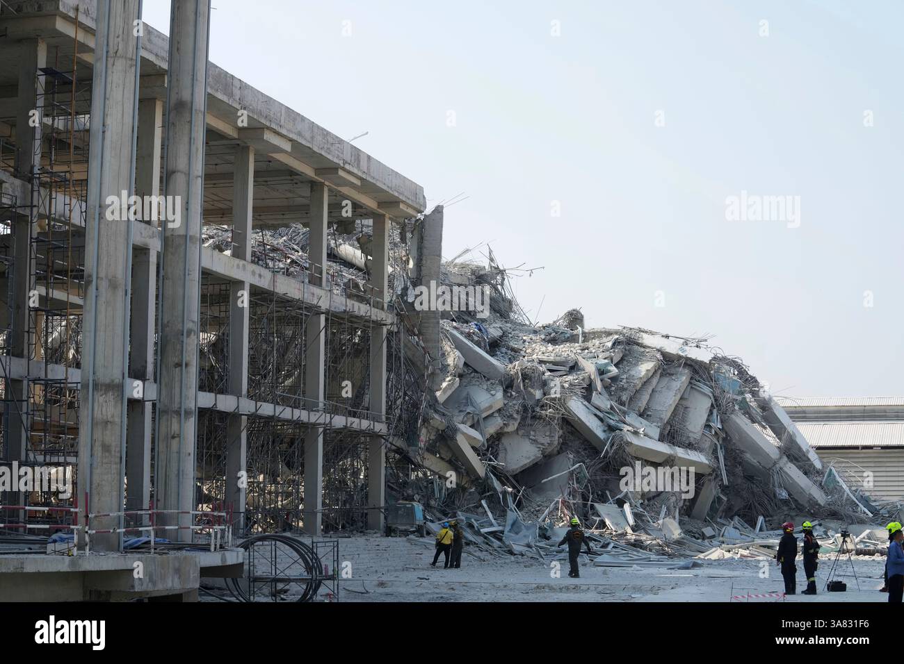 Rescuers walk at the site of a high-rise building under construction ...