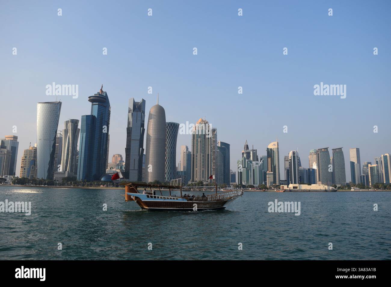 Past meets future: A traditional wooden dhow sails across Doha Bay, framed by Qatar's ...