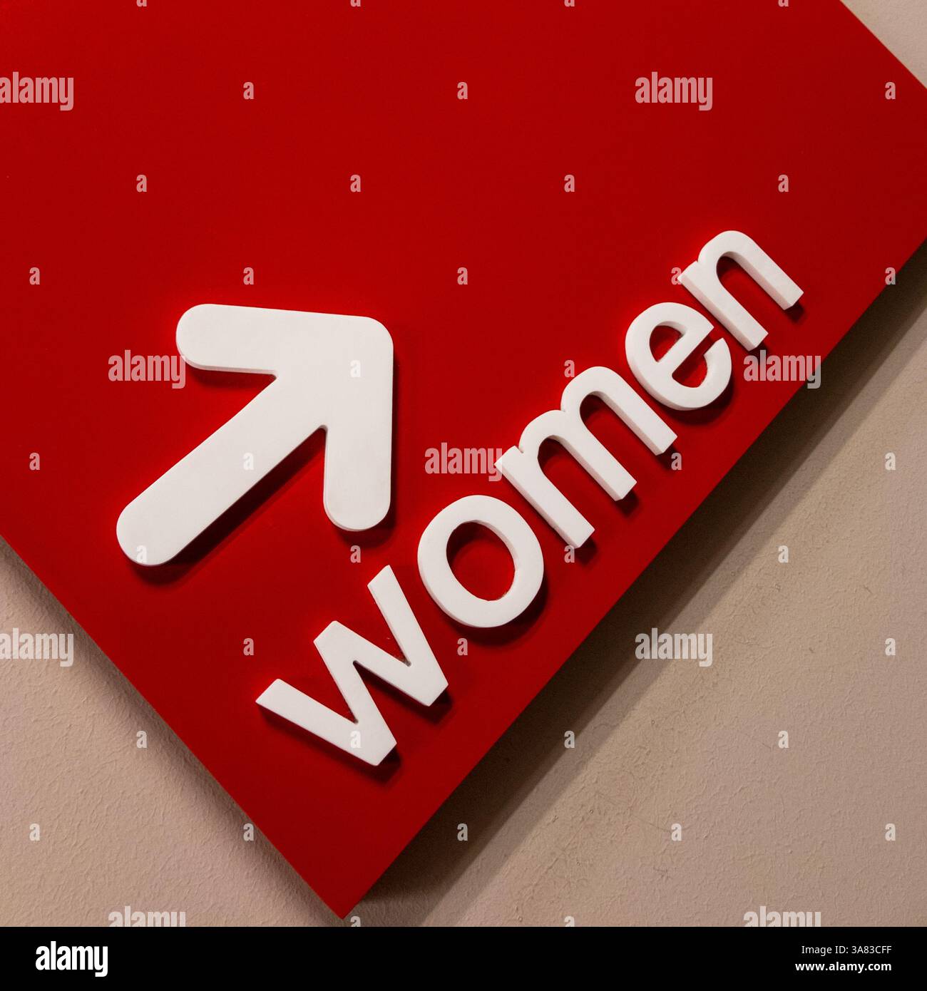 Red wall-mounted sign with the word women and an arrow pointing to the ...