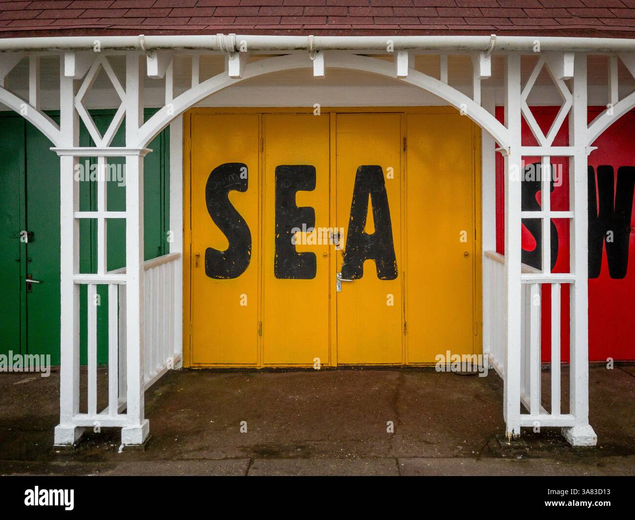 Beach chalet with yellow doors featuring the word ‘Sea’ painted in ...