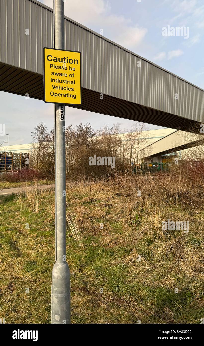yellow caution warning sign at a cross walk by a industrial area ...