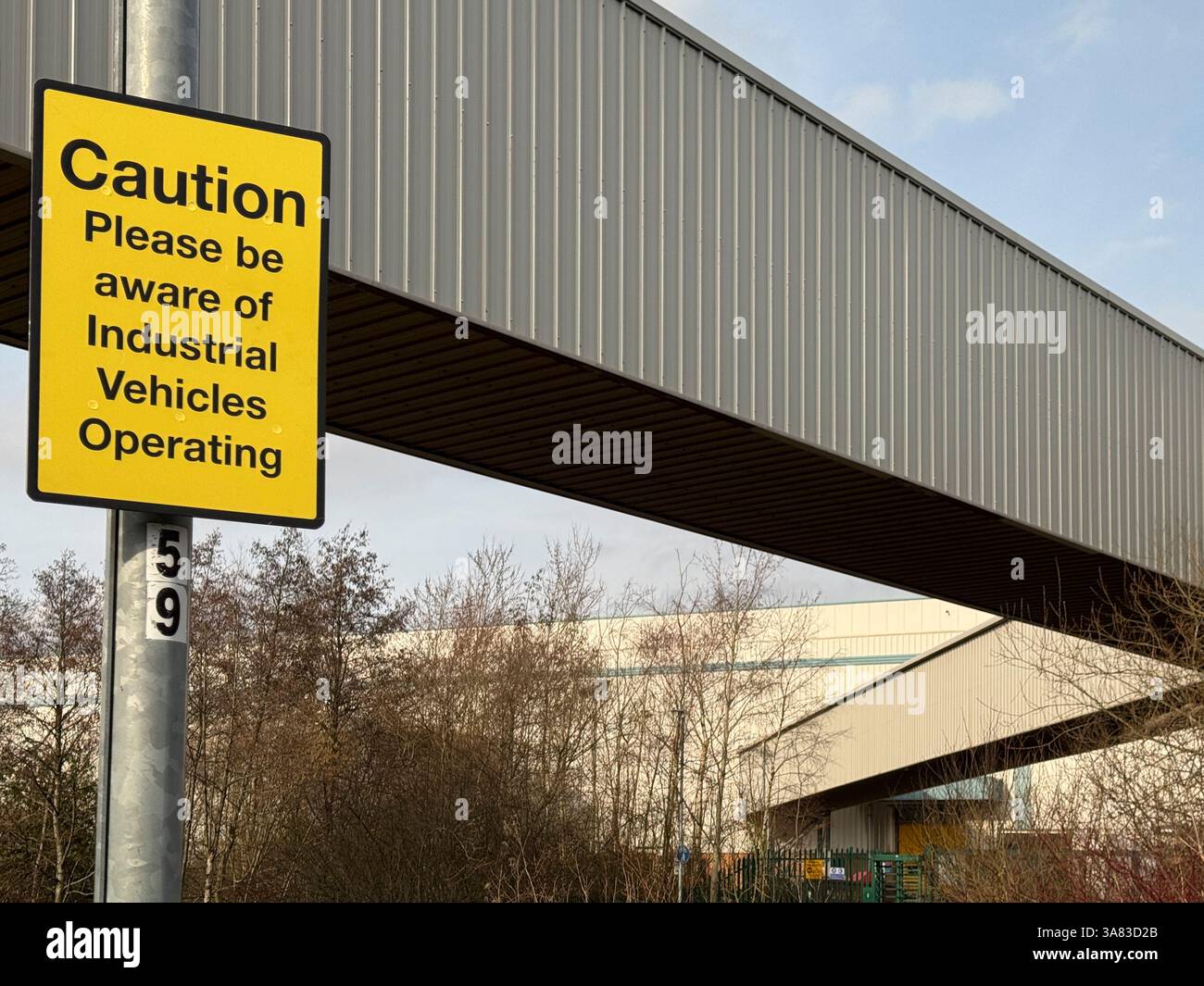 yellow caution warning sign at a cross walk by a industrial area ...