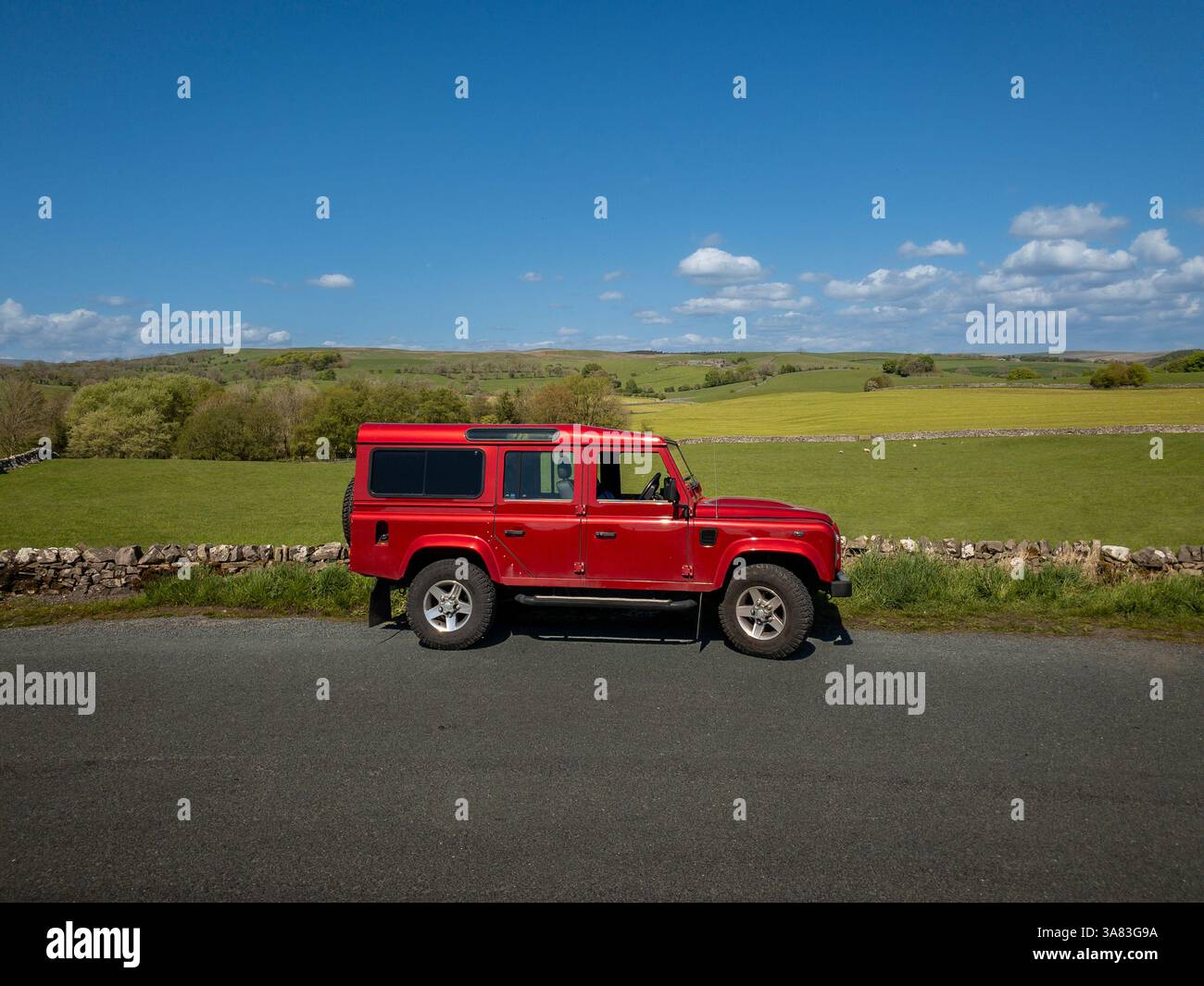 Metallic red Land Rover Defender 110 parked roadside in Malhamdale ...