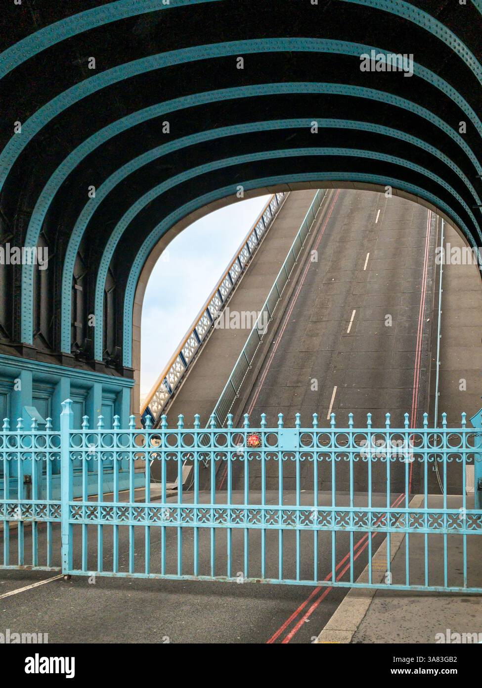 Ornate blue gates closed across Tower Bridge as the road lifts to allow ...