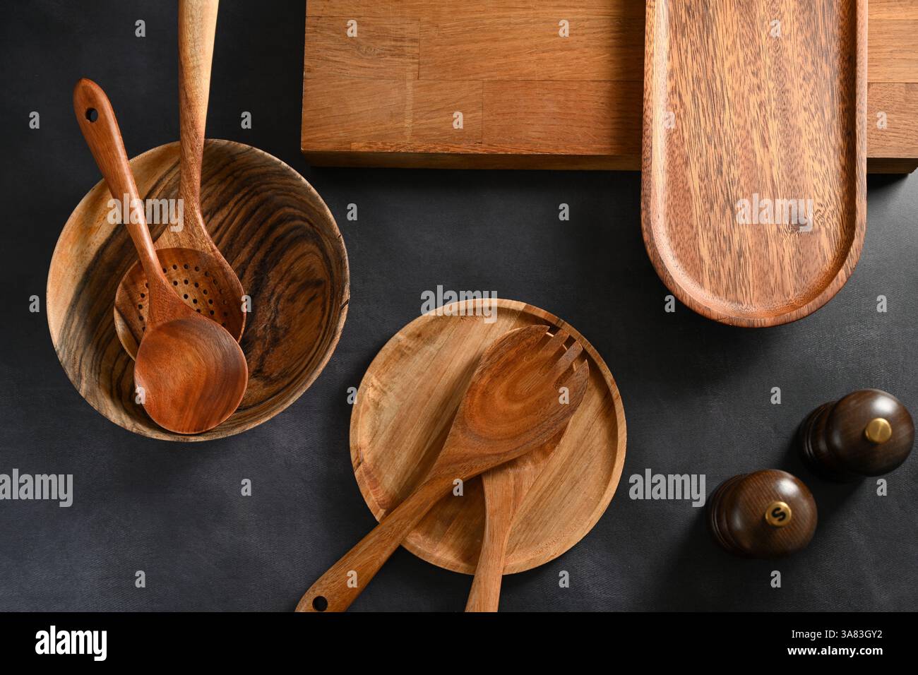 Wooden kitchen spoons, plates on black background Stock Photo - Alamy