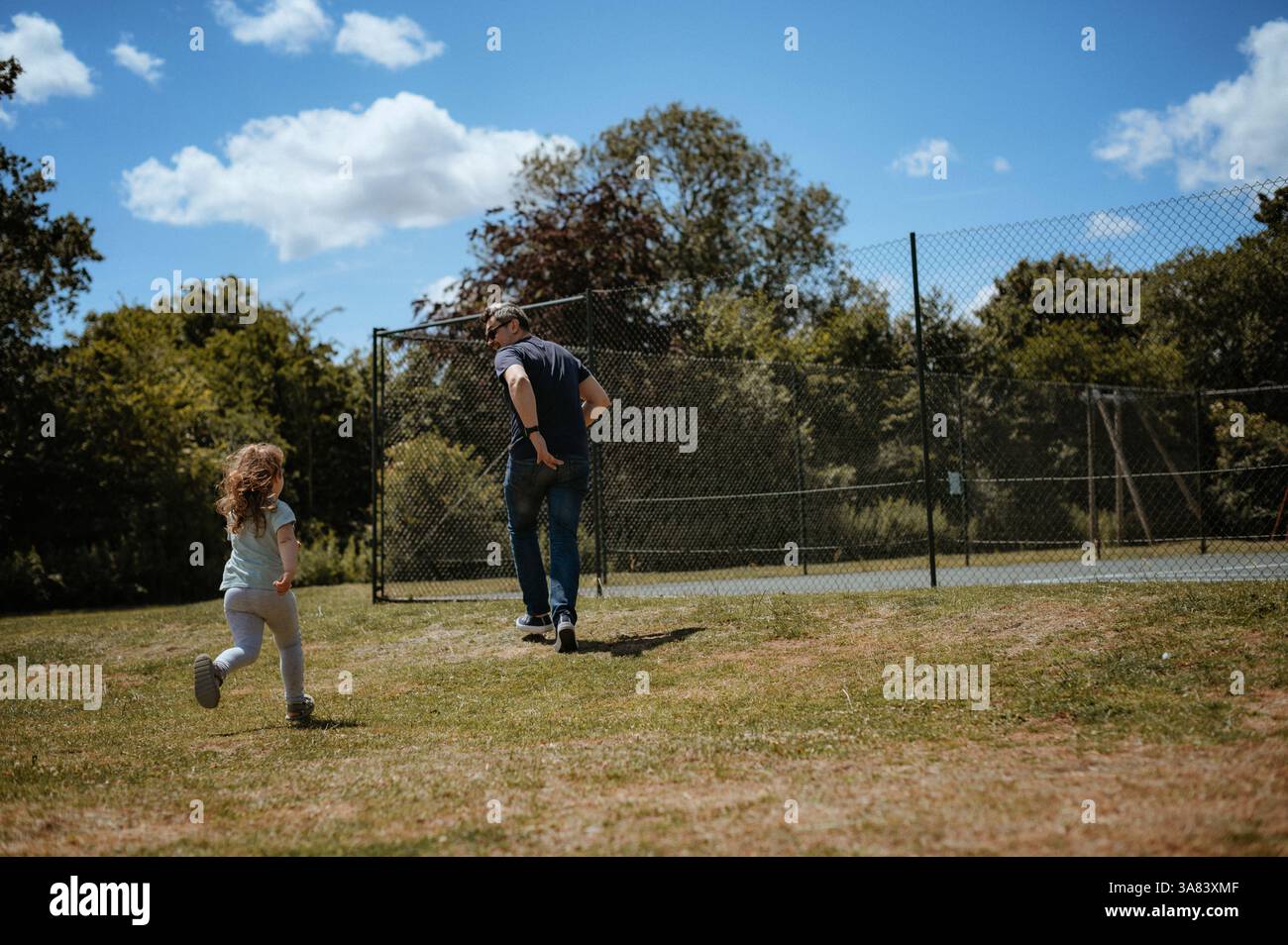 A girl runs after dad on the playground Stock Photo - Alamy