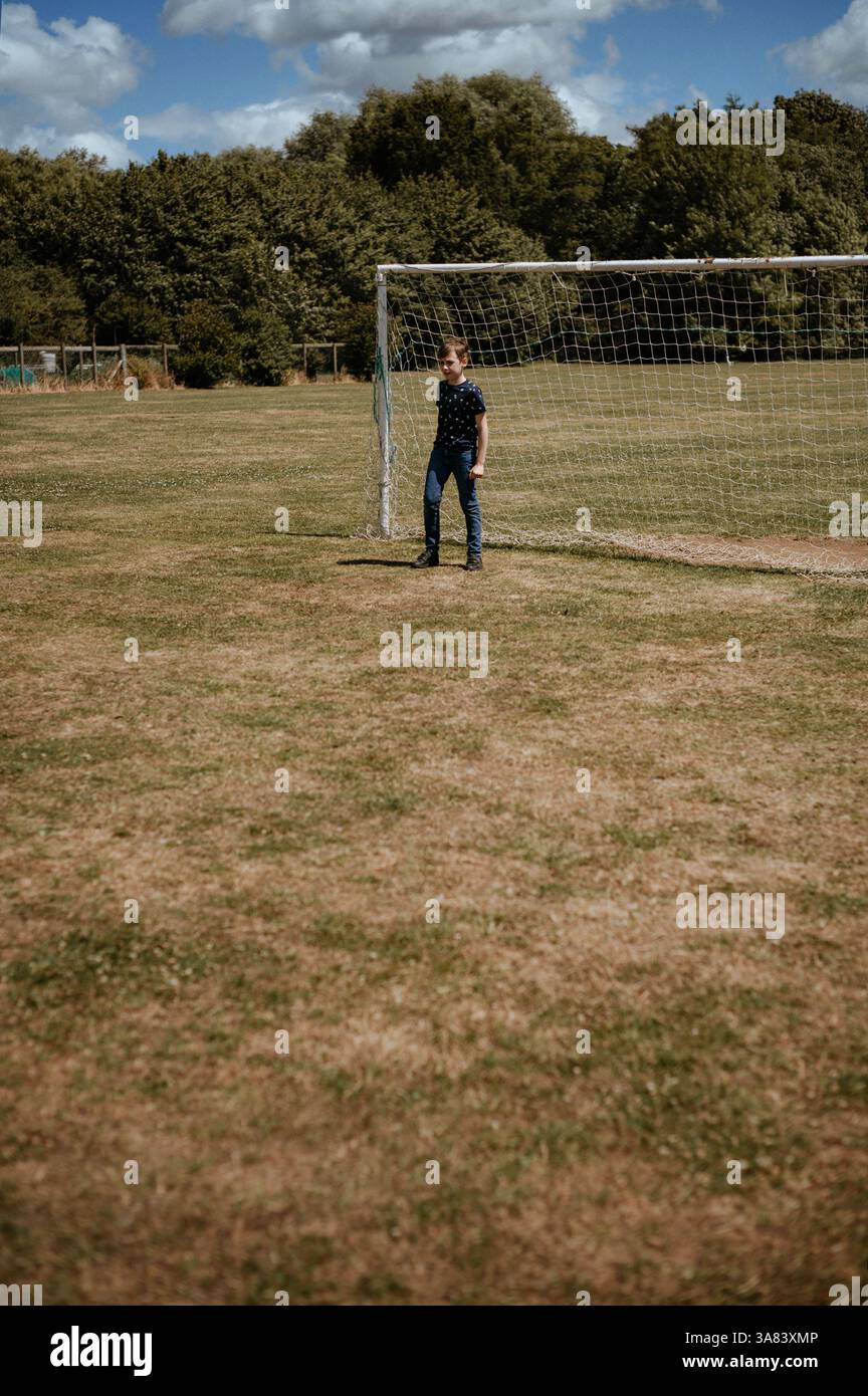 A boy stands in front of a football goal. Goalkeeper Stock Photo - Alamy
