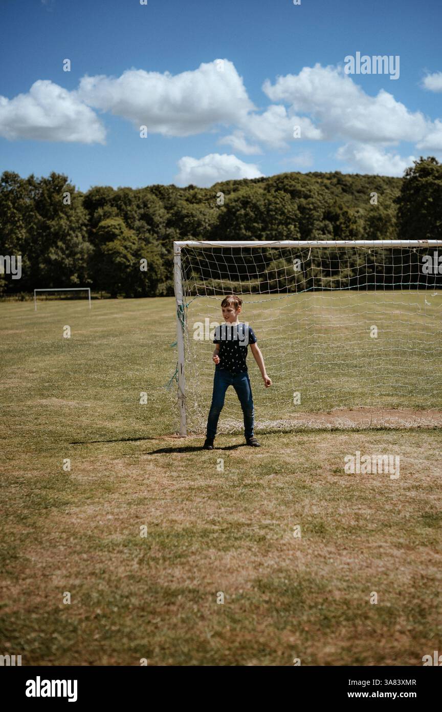 A boy stands in front of a football goal. Goalkeeper Stock Photo - Alamy