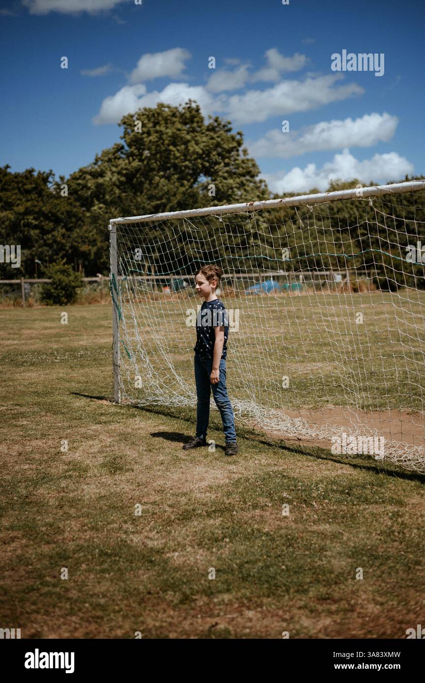 A boy stands in front of a football goal. Goalkeeper Stock Photo - Alamy