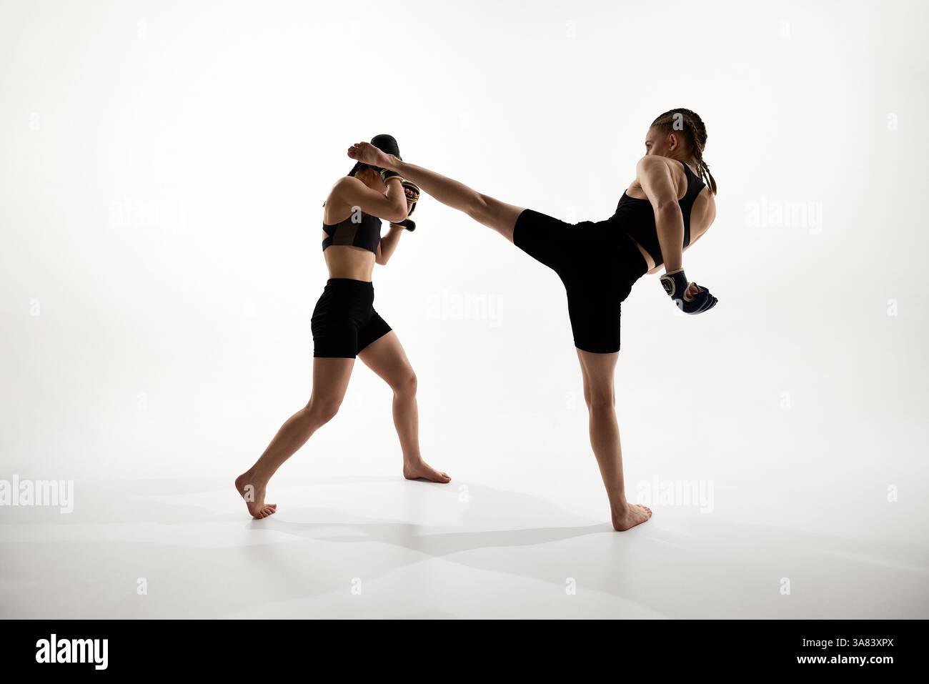 Strong female athletes in active stance, executing high kick and ...