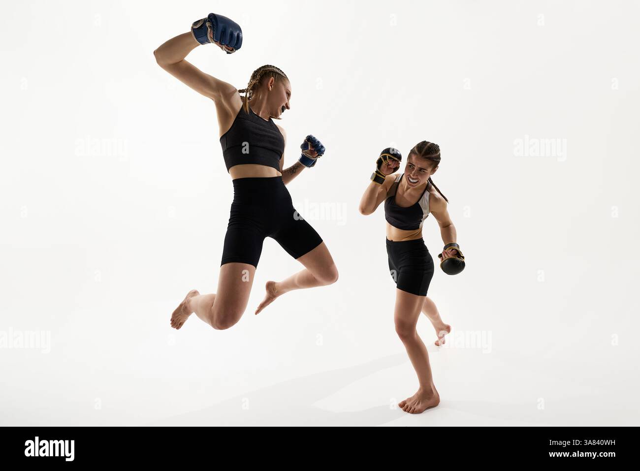Two women fighters in mid-battle, wearing boxing gloves and sportswear ...
