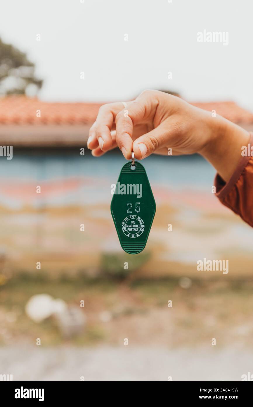 Hand holds vintage motel key tag outside Alpine, Texas motel mural ...