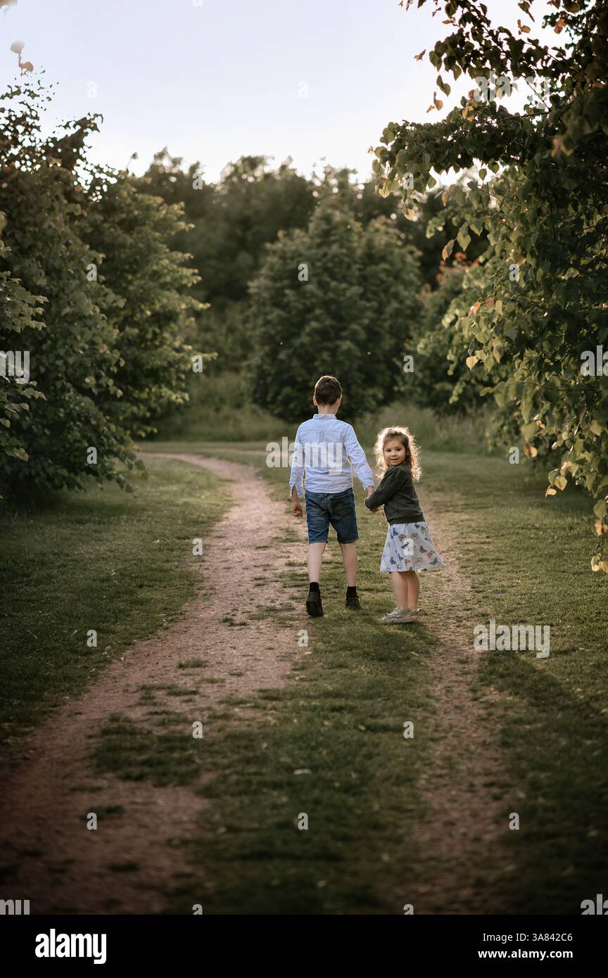 Brother and sister go on the road in the park. Sister looked back Stock ...