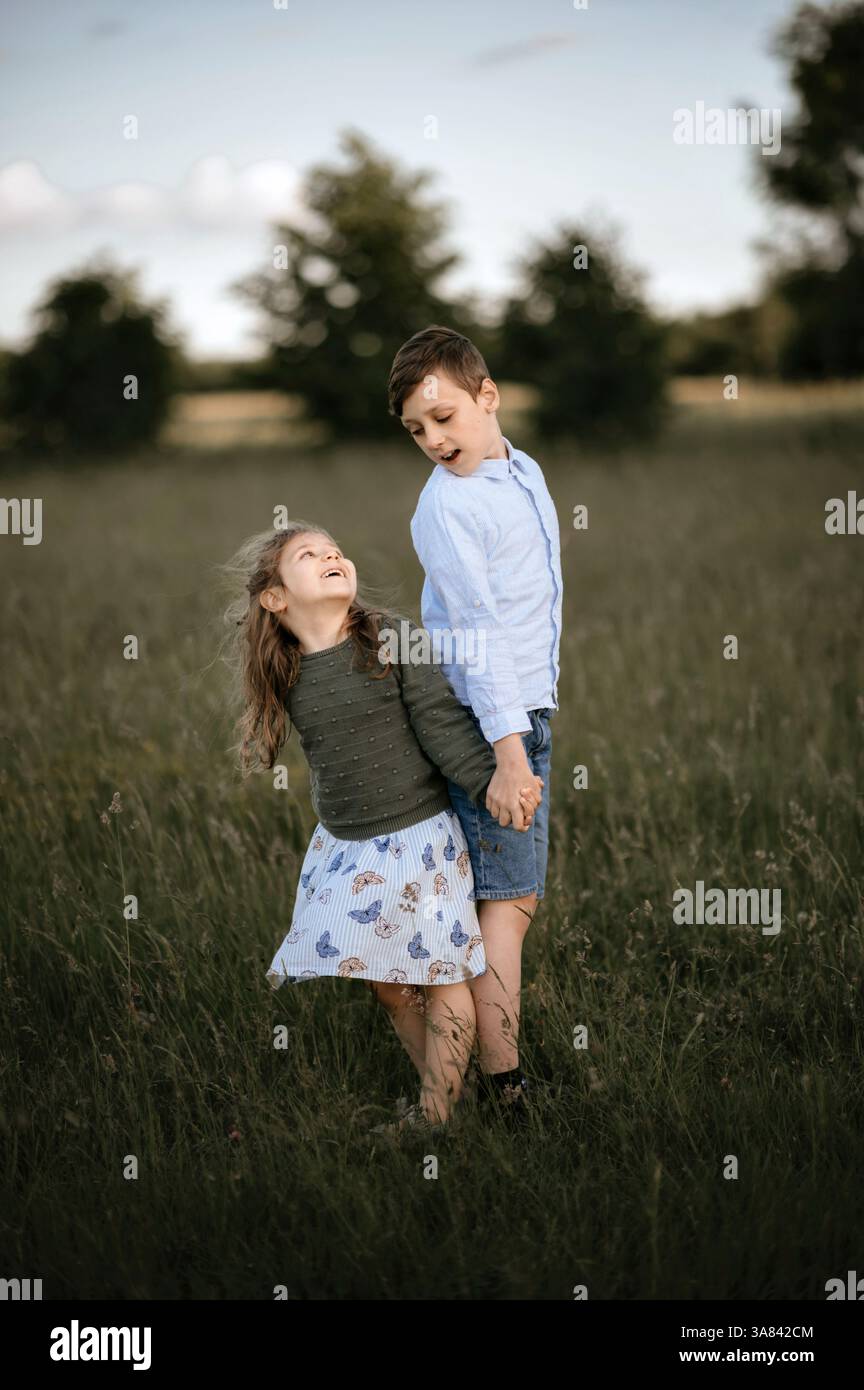 Siblings stand together and look back at each other. holding hands ...