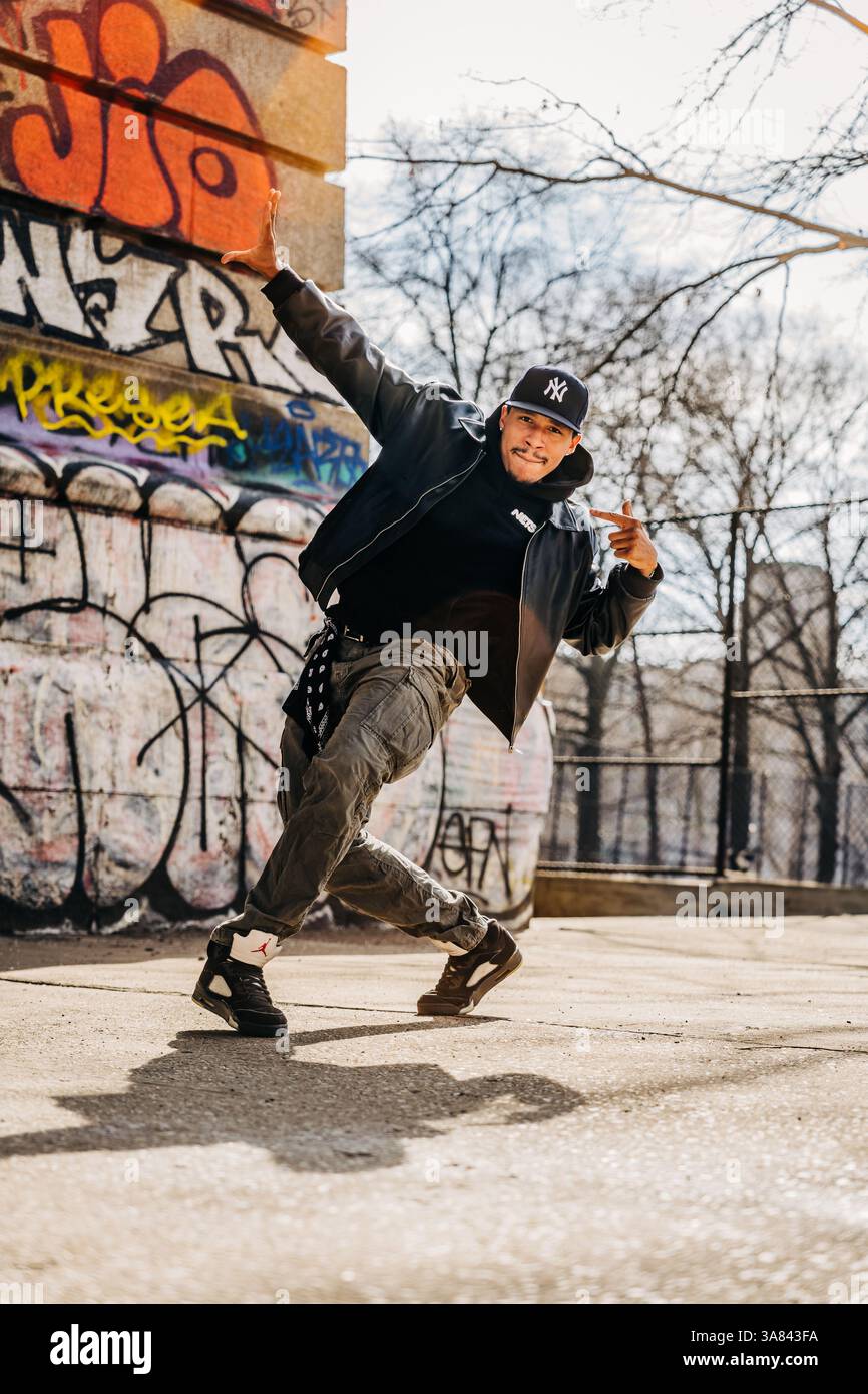 Street dancer strikes animated pose near graffiti wall outdoors Stock Photo - Alamy