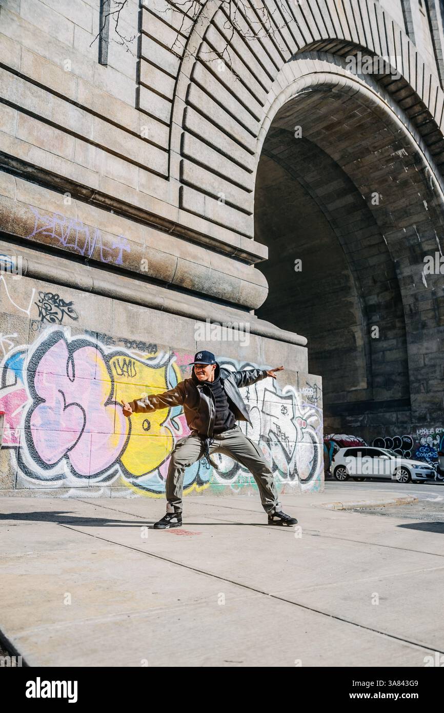 Street dancer poses wide near colorful graffiti and stone arch Stock ...