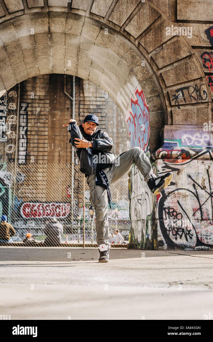 Street dancer in mid-pose under graffiti-covered archway Stock Photo ...