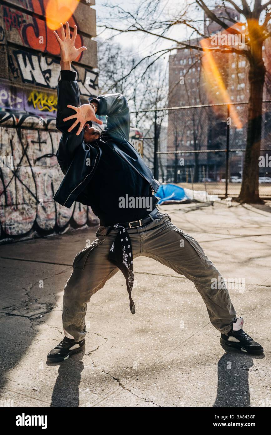 Dancer strikes dramatic pose near graffiti wall in afternoon sun Stock ...