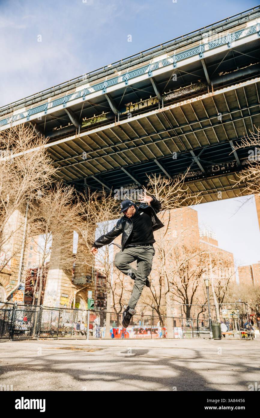 Dancer mid-jump under bridge in NYC urban playground scene Stock Photo ...